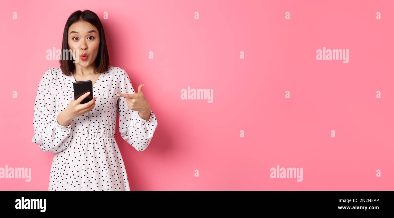 Online shopping and beauty concept. Amazed asian woman pointing finger ...