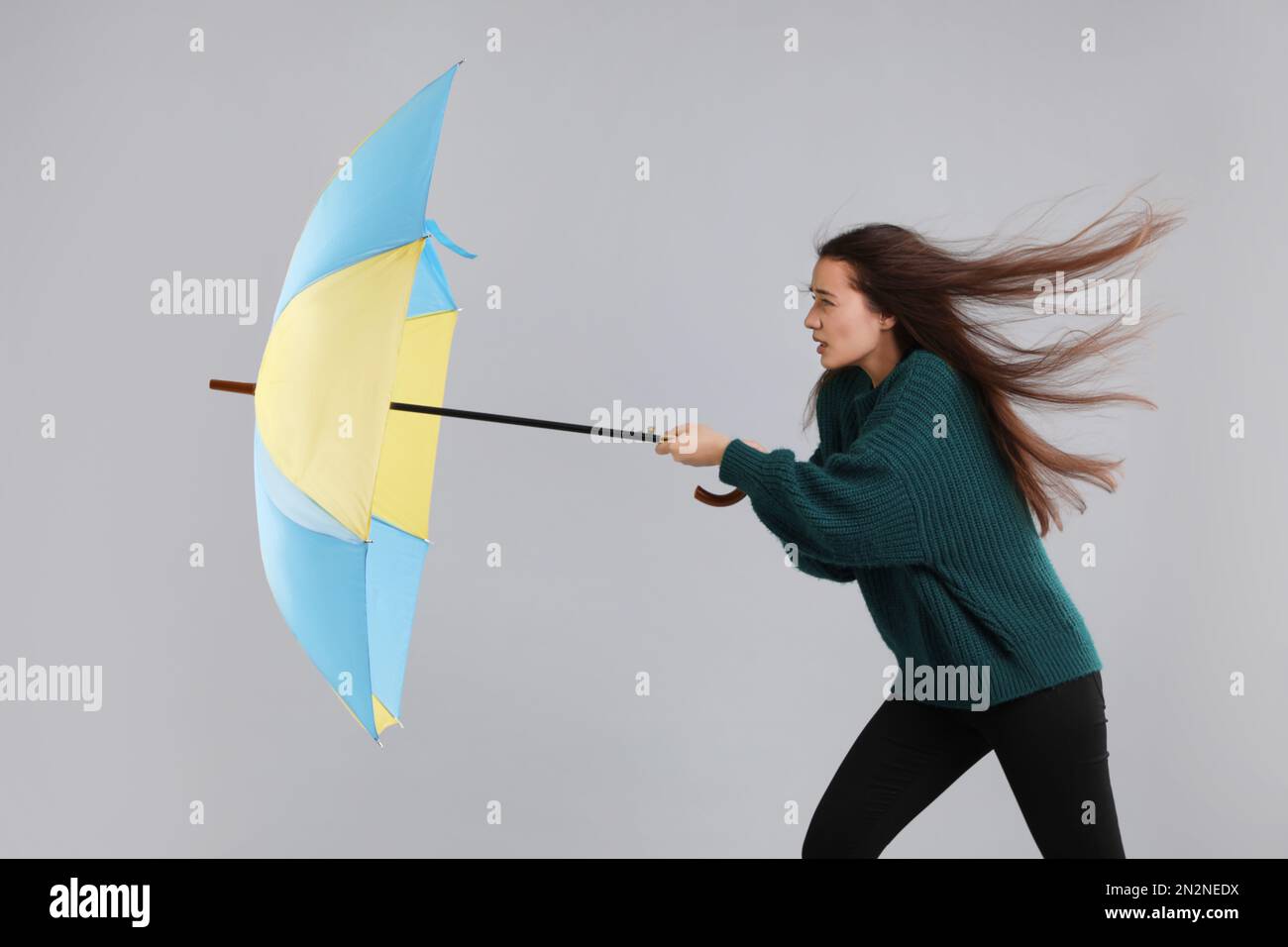 Woman with umbrella caught in gust of wind on grey background Stock ...