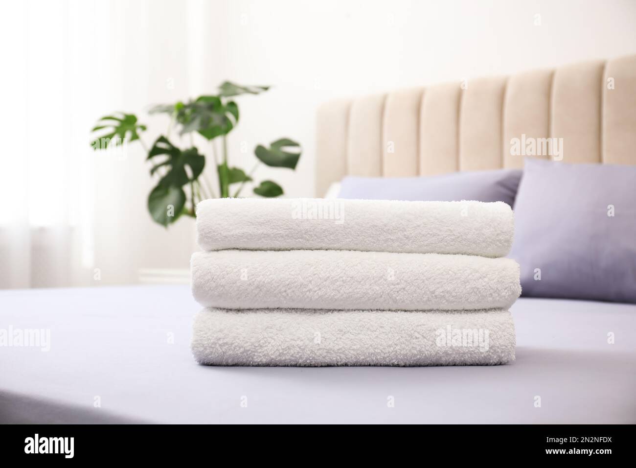 Stack of clean towels on bed indoors Stock Photo - Alamy