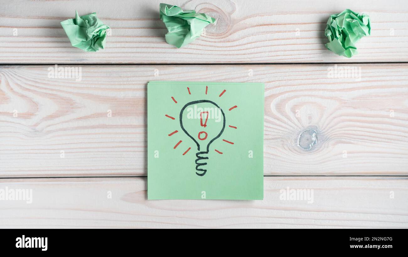 Flat lay of green sticker note with light bulb drawn with black marker ...