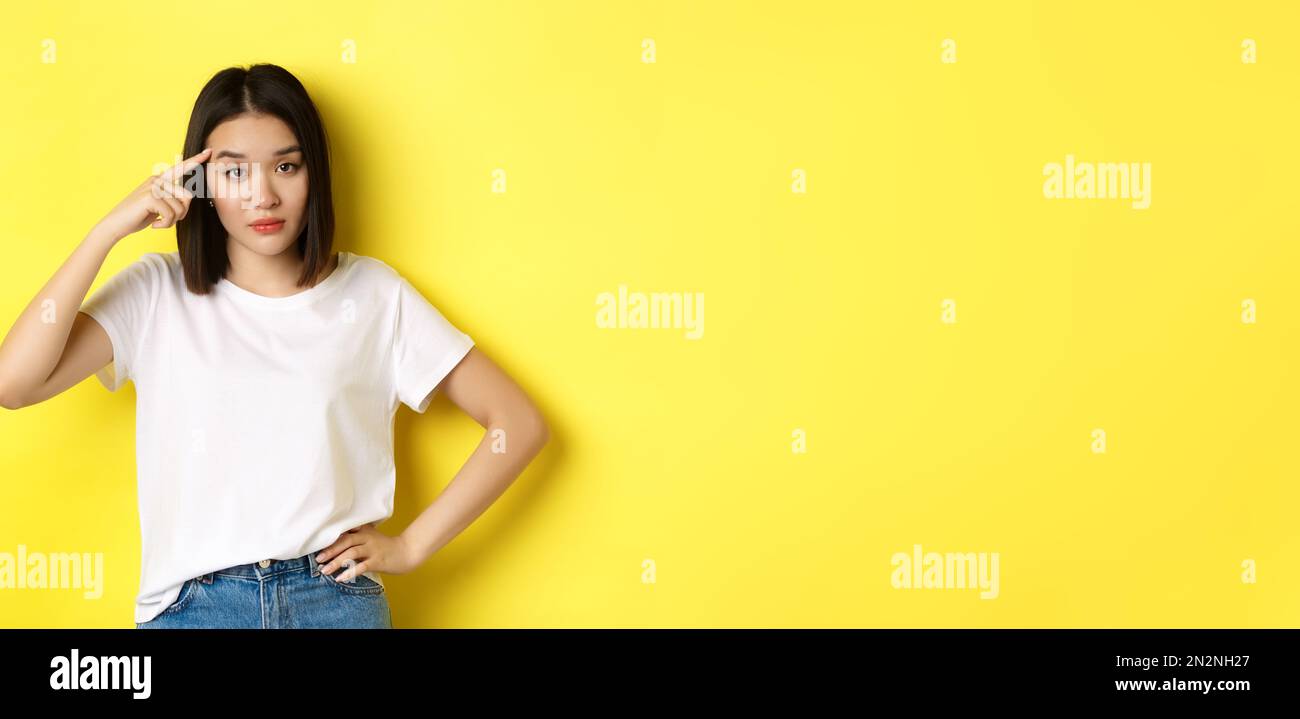 Annoyed young asian woman scolding someone stupid, pointing finger at ...