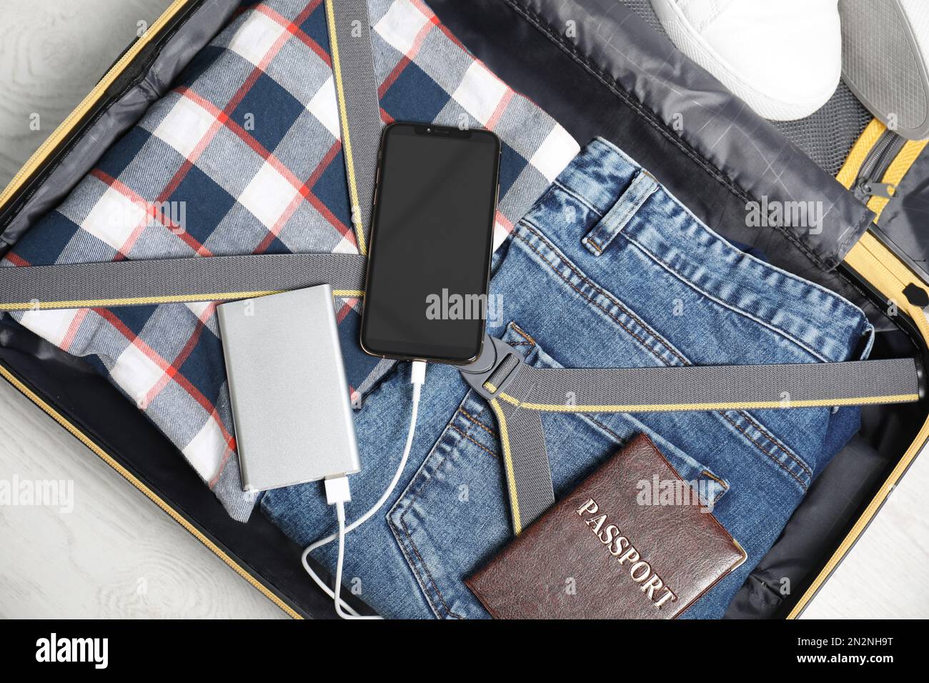 Smartphone charging with power bank, passport and clothes in open ...