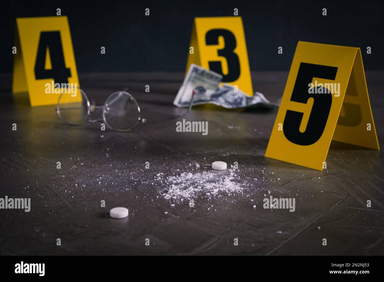 Pill and white powder near crime scene marker on grey stone table ...