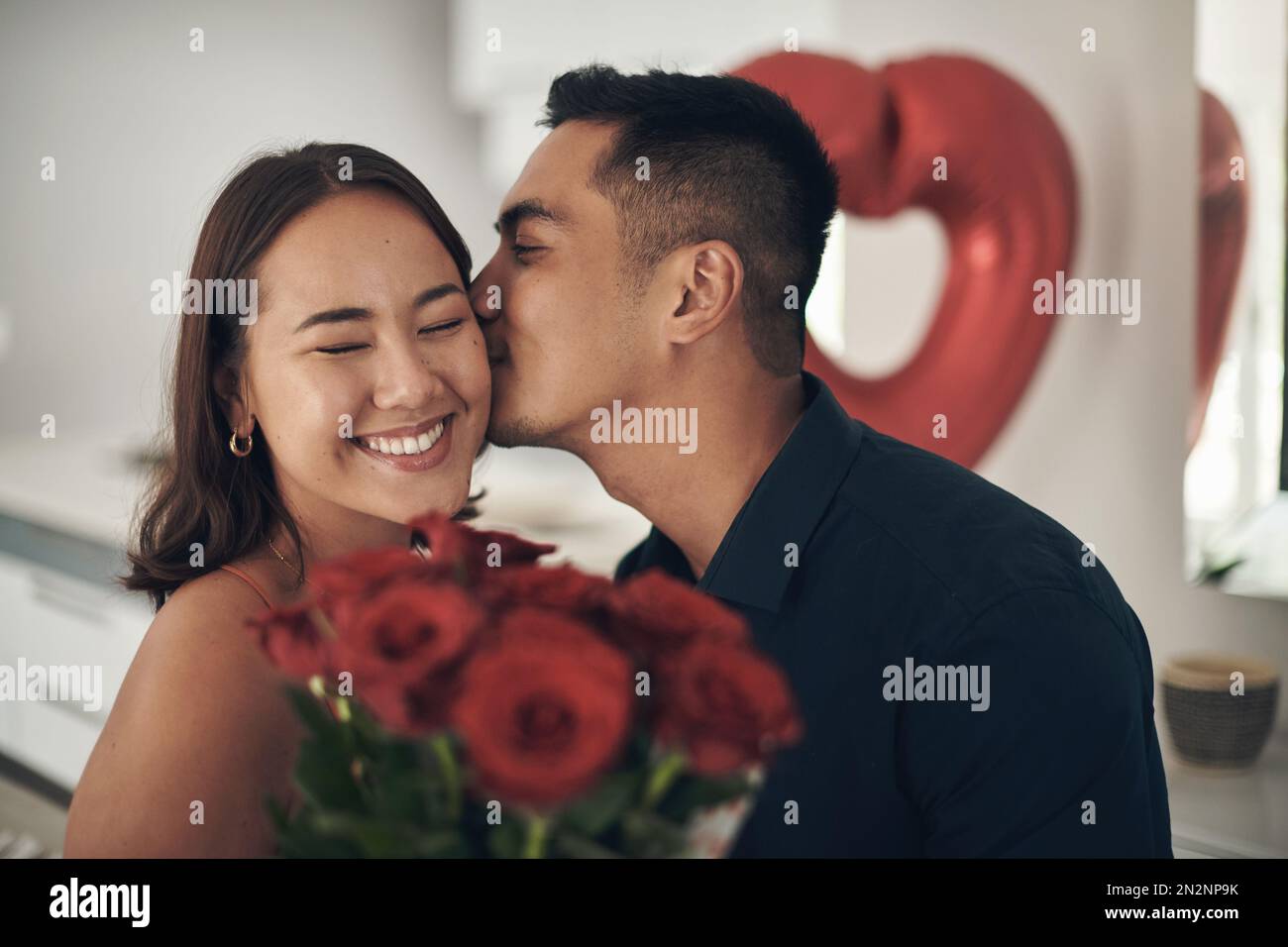 Love, rose and valentines day with a couple kissing in their home, in ...