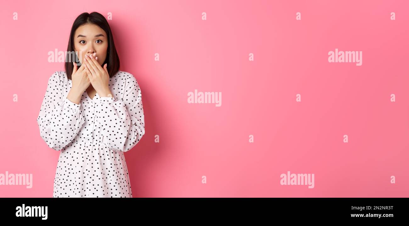 Image of surprised asian female model gasping, cover mouth and looking ...