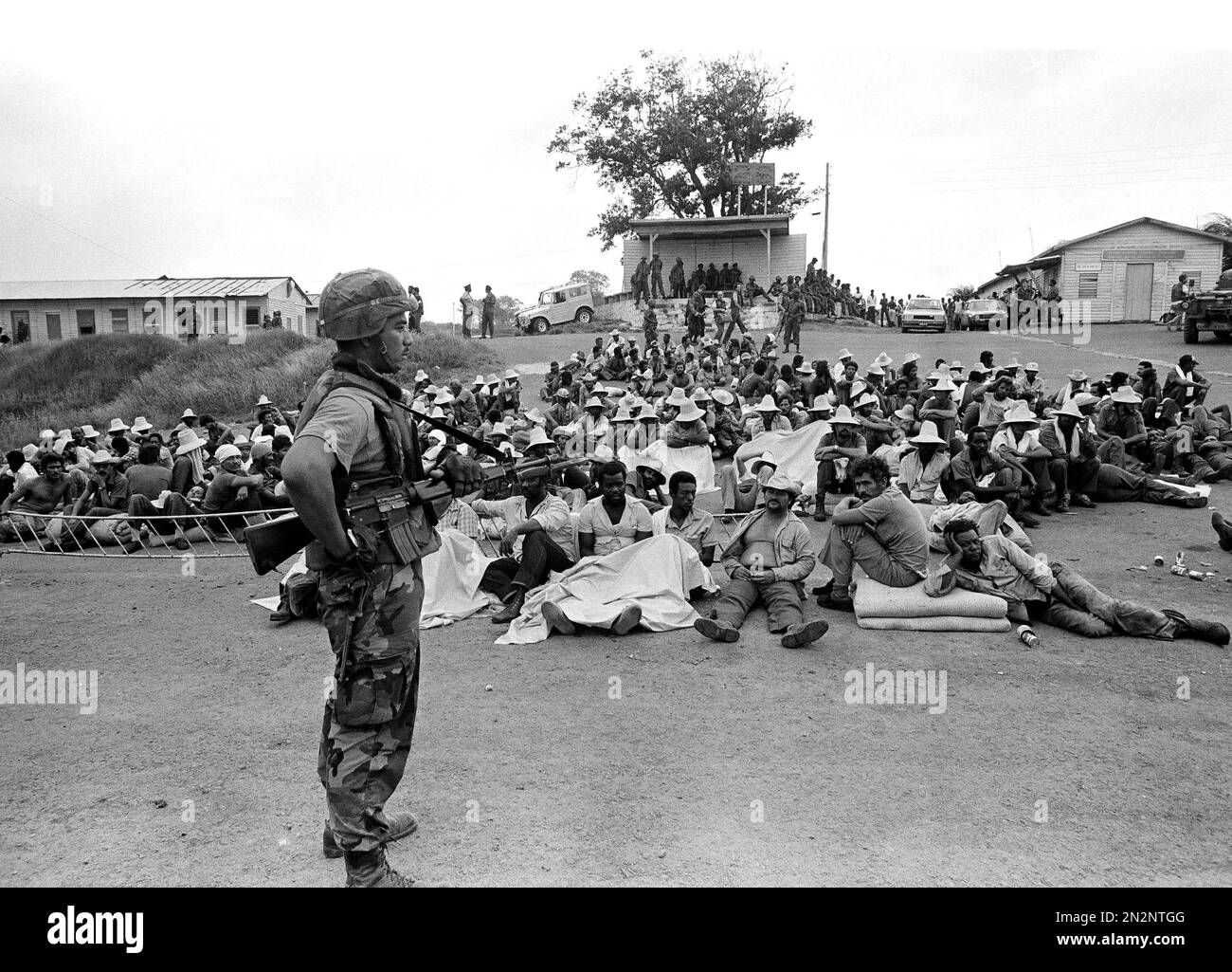A soldier stands guard over a group of Cuban prisoners captured during ...