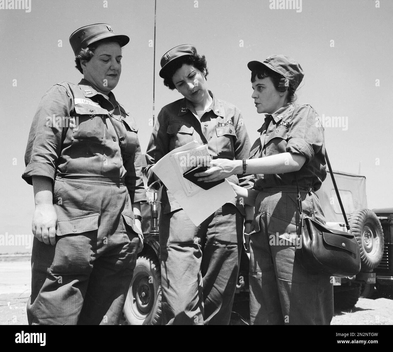 Three Army nurses, part of a group of 17, look over information sheets ...