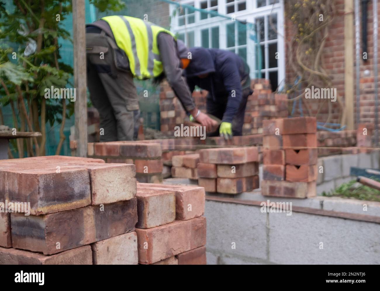 Two construction workers laying bricks as part of a renovation of an ...