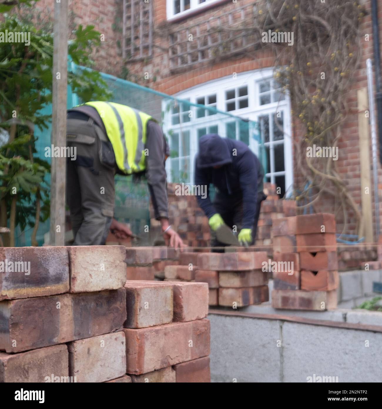 Two construction workers laying bricks as part of a renovation of an ...