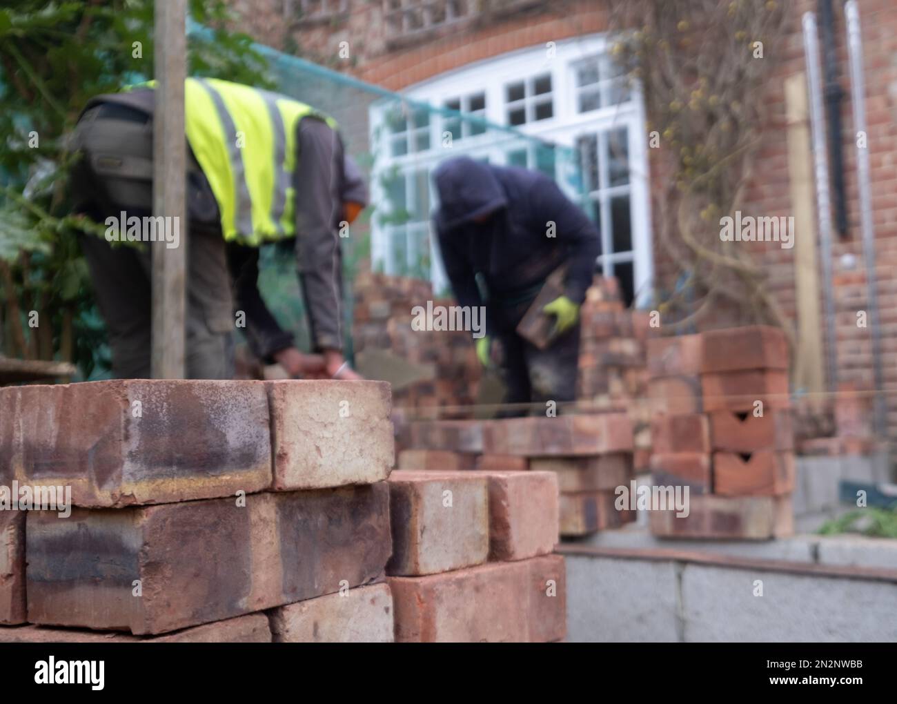 Two construction workers laying bricks as part of a renovation of an ...