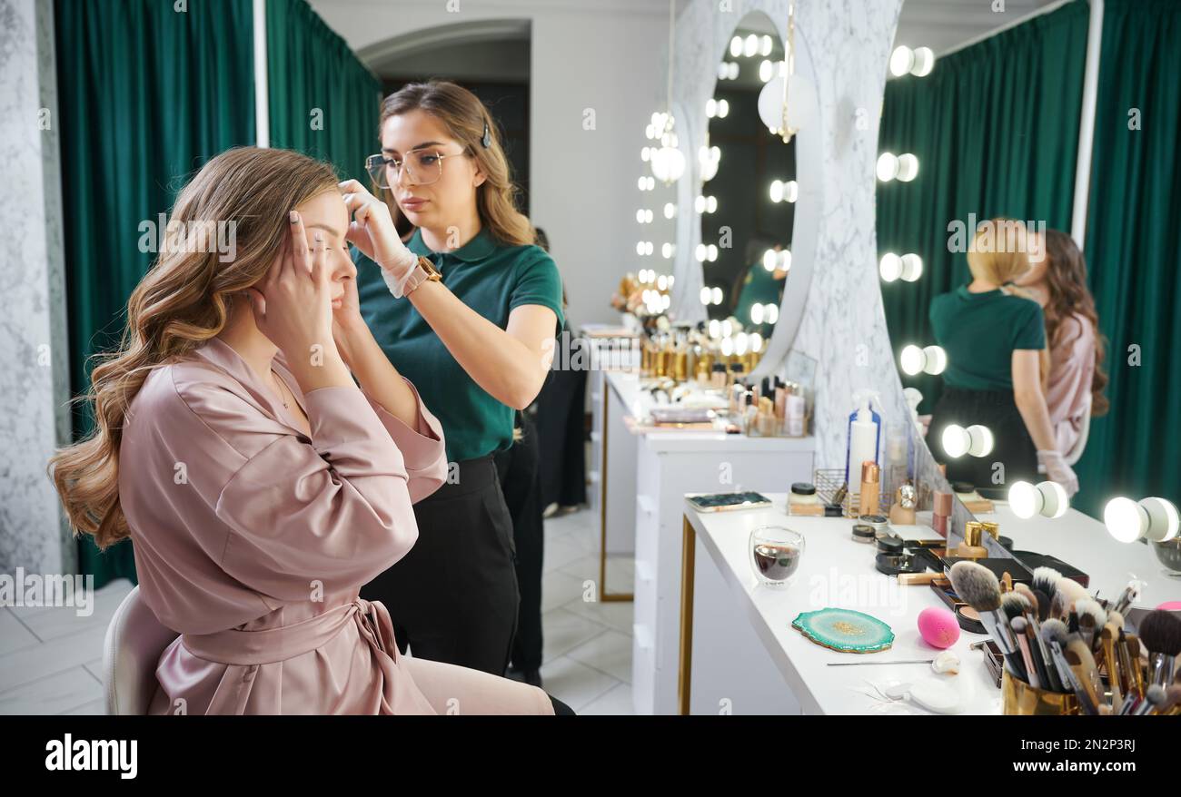 Female stylist in sterile gloves holding client hair lock and pulling ...