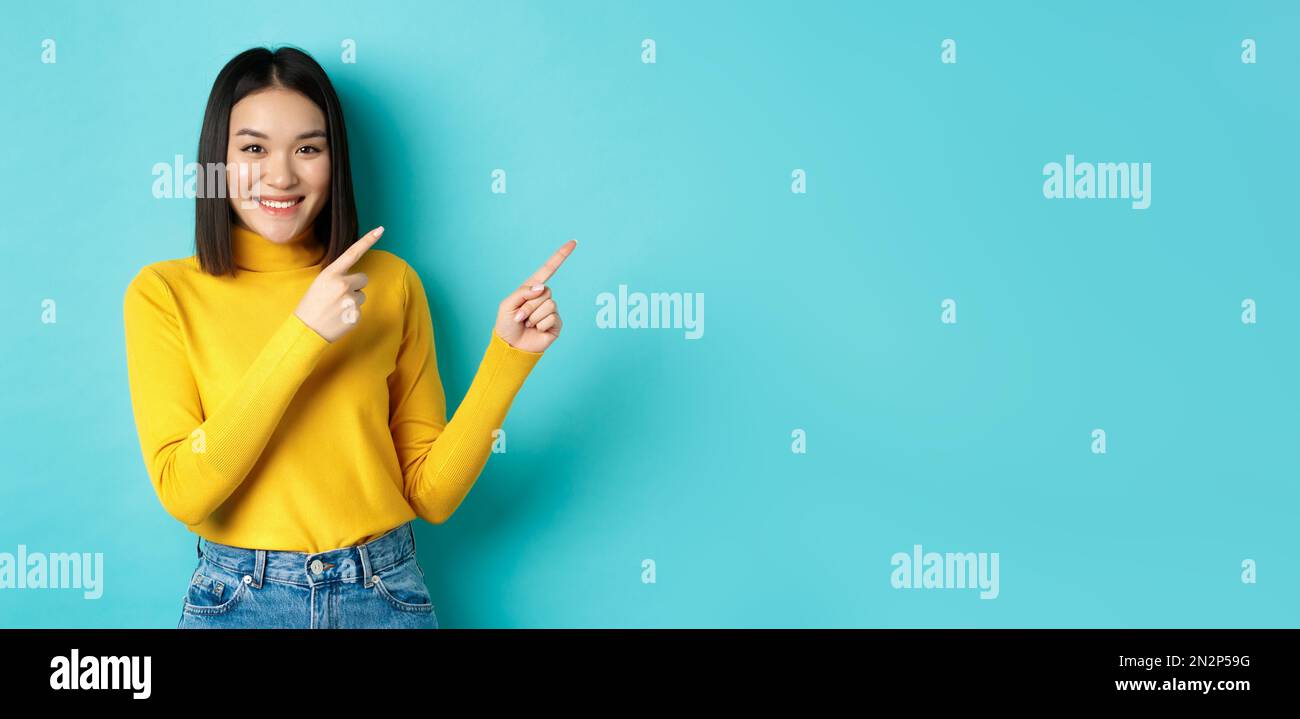 Shopping concept. Attractive asian girl in trendy sweater showing ...