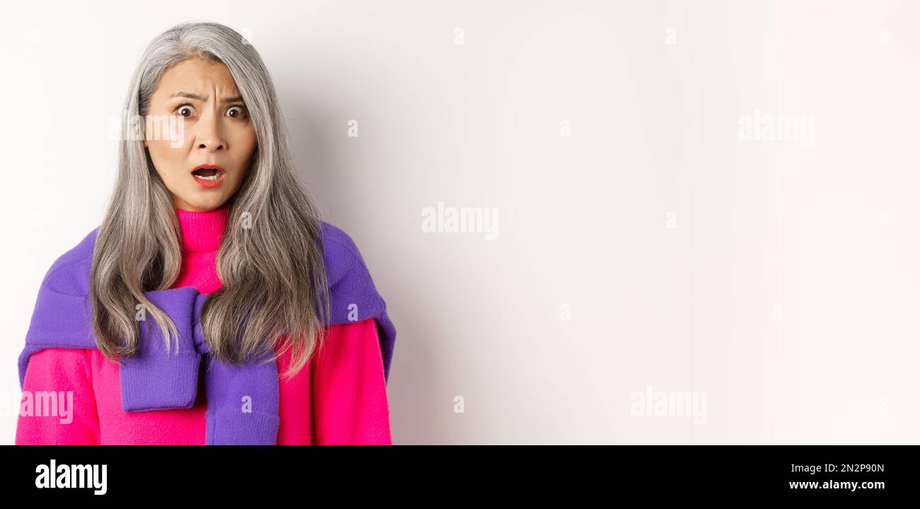 Close-up of shocked asian senior woman gasping, staring with confused ...