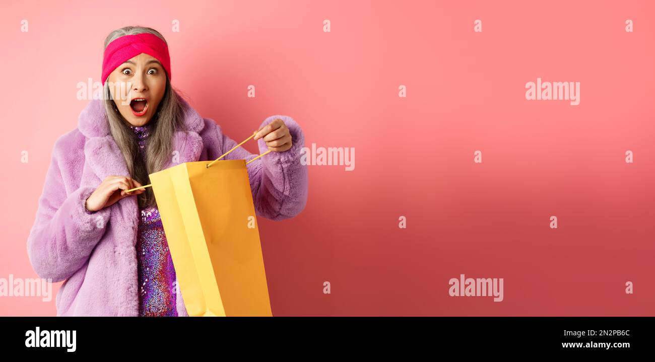 Shopping and fashion concept. Surprised asian grandmother open shop bag ...