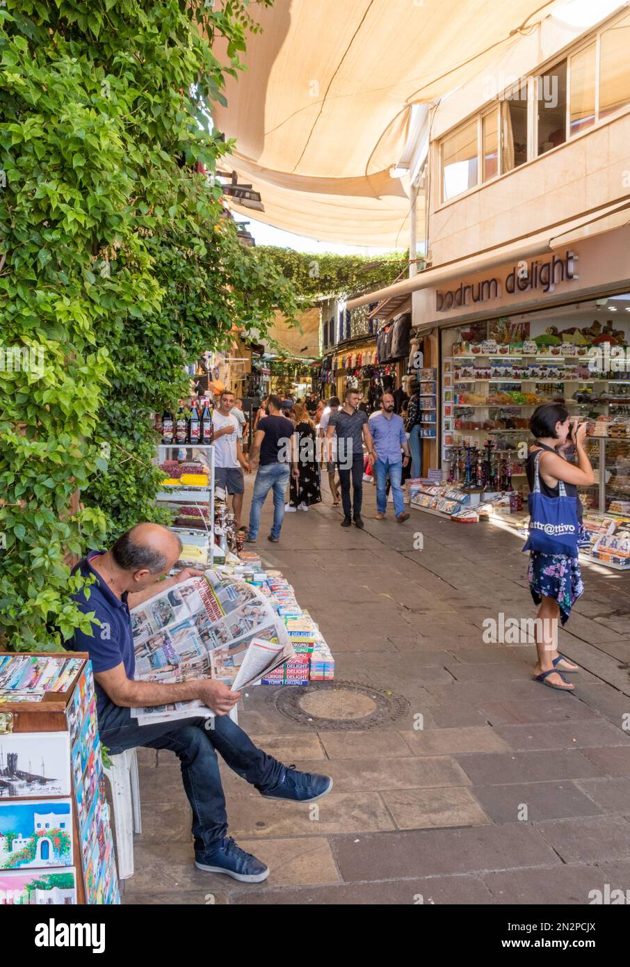 man looking at newspaper in shopping centre Stock Photo - Alamy