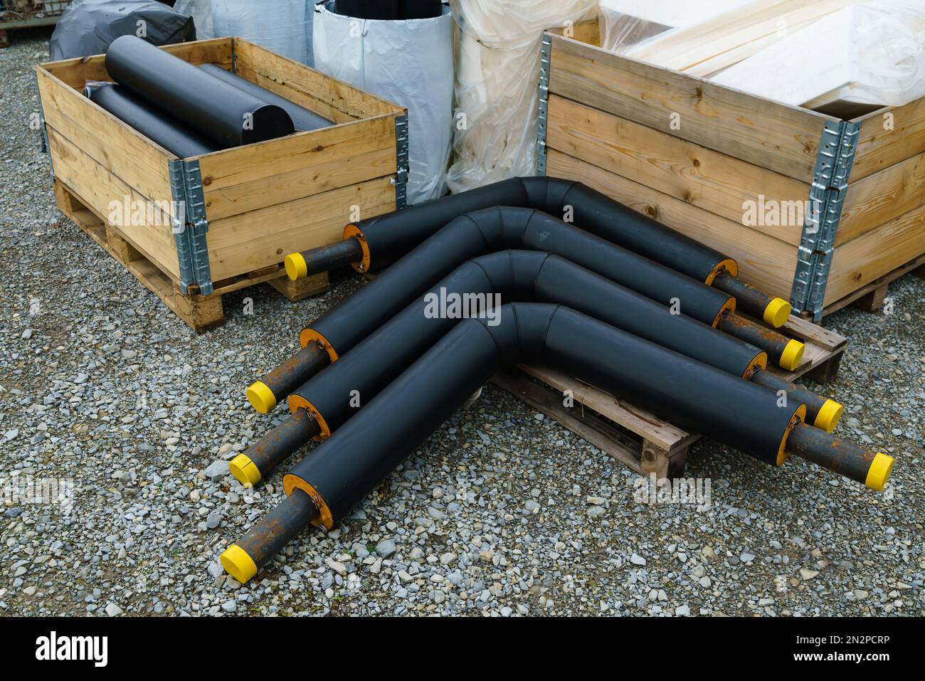 Angled insulated heating pipes with yellow plastic plugs lie on the ...