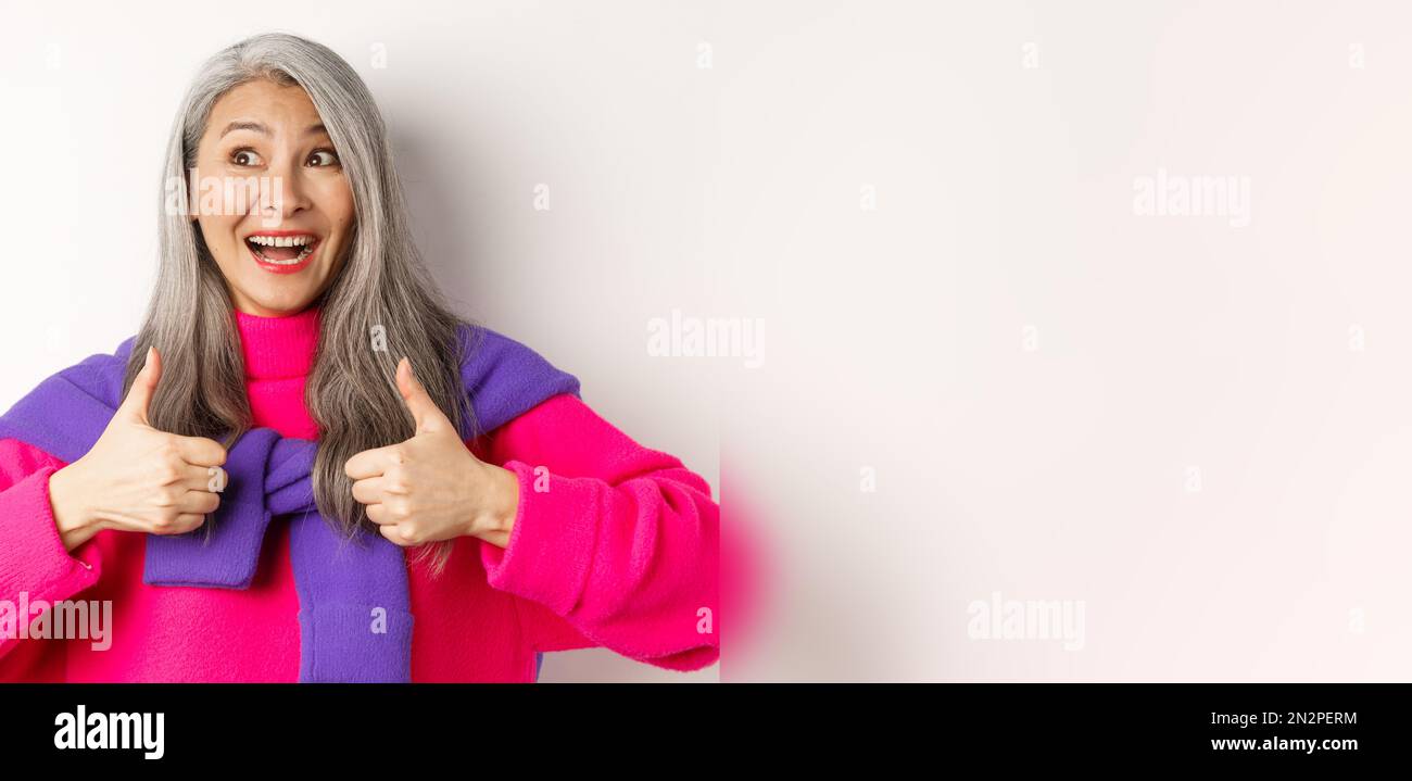 Excited and amazed asian elderly woman showing thumbs-up in approval ...
