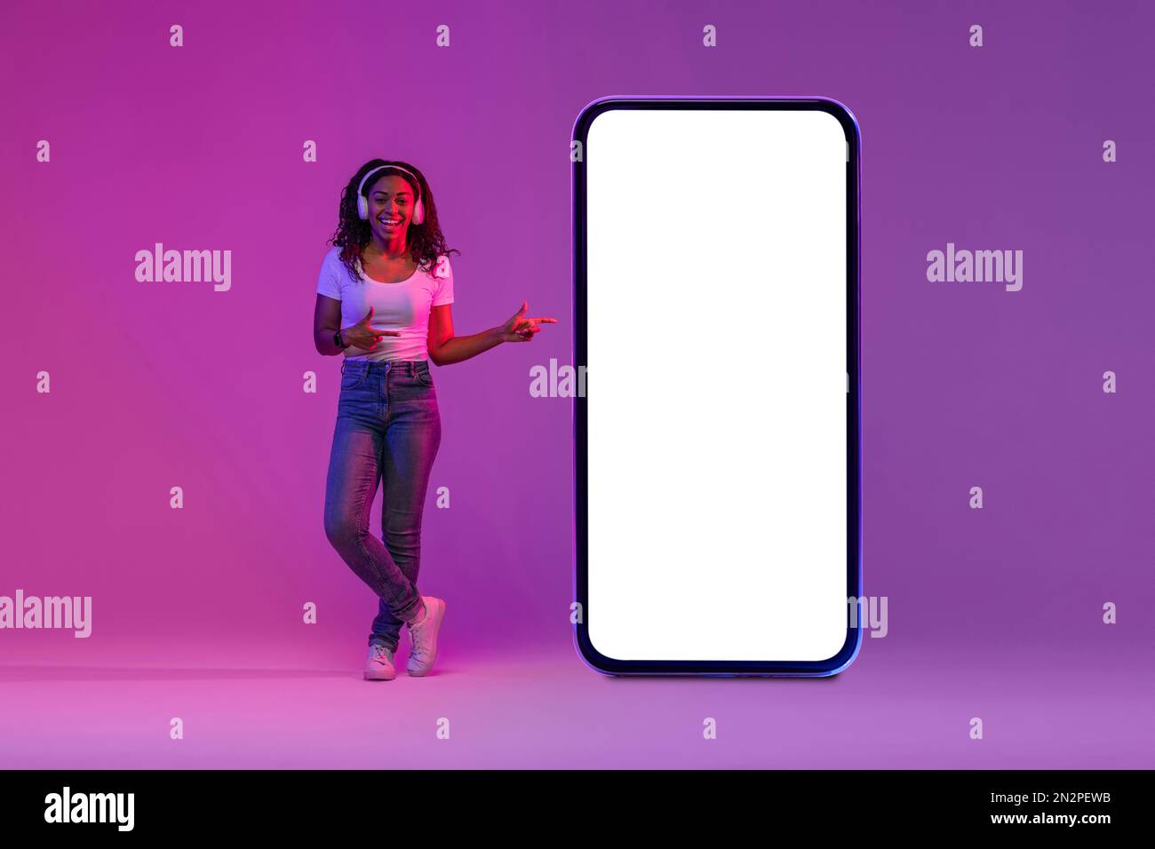 Mobile App. Happy Black Female Wearing Headphones Pointing At Big Blank Smartphone Stock Photo ...