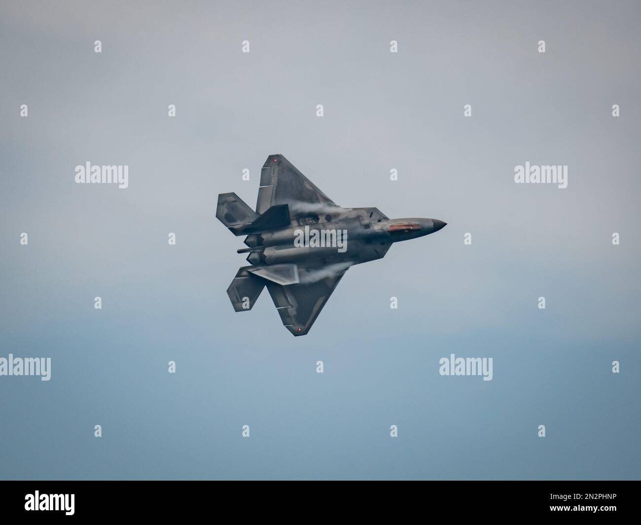 A closeup of Lockheed Martin F-22 Raptor flying in the sky at an air ...