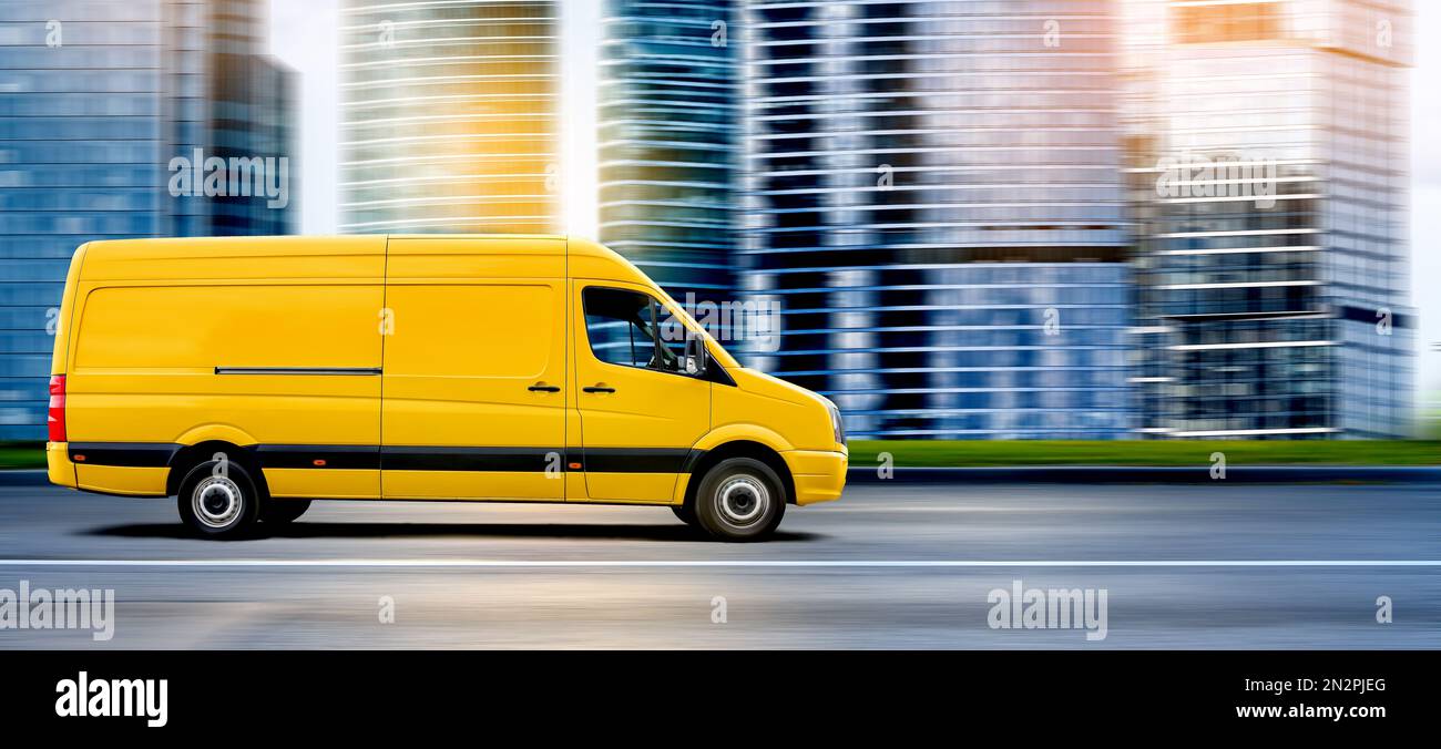 Yellow Van driving on a city road at sunset in front of a modern ...