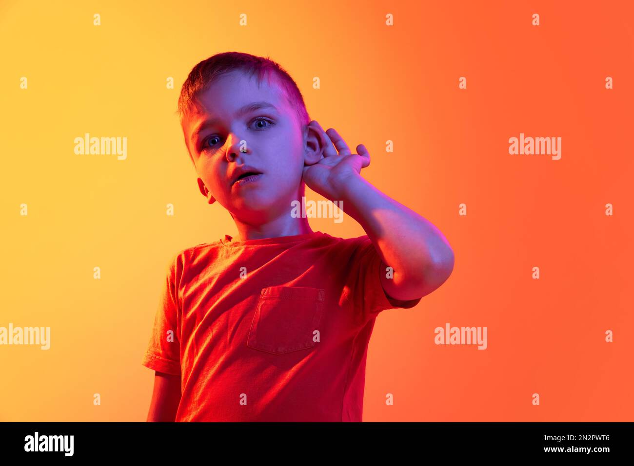 Overhearing. Portrait of little boy, child posing with hand to ear over ...