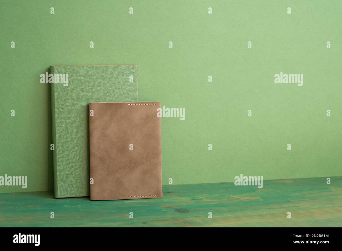 Green and brown diary notebook on wooden desk. green wall background ...