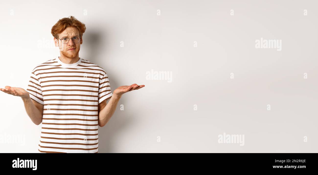 Confused boyfriend with red hair shrugging, spread hands sideways and ...