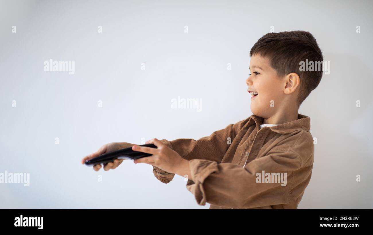 Smiling caucasian little child with remote control switches channels on ...