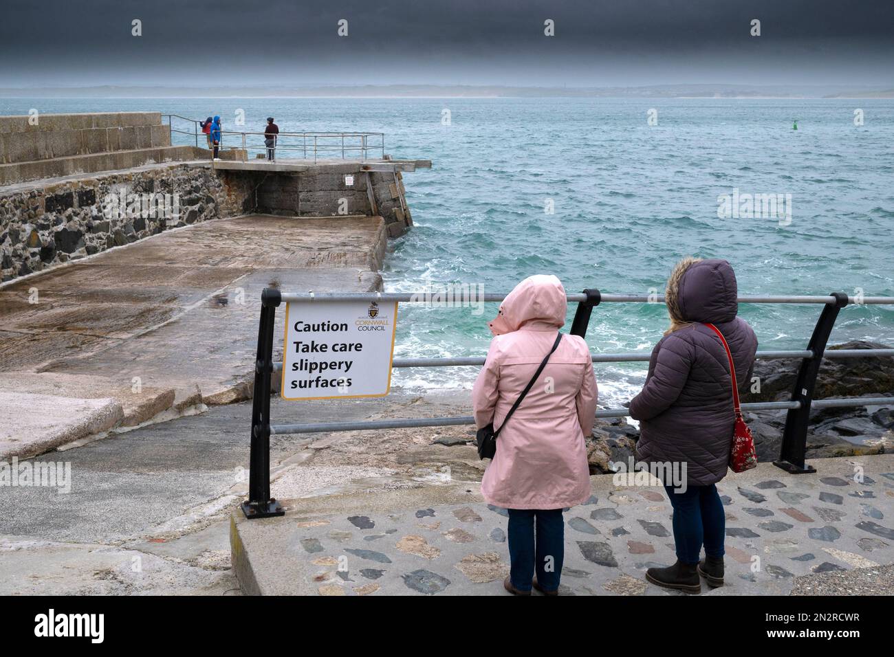 UK weather. Visitors standing on The Wharf on a rainy chilly miserable ...