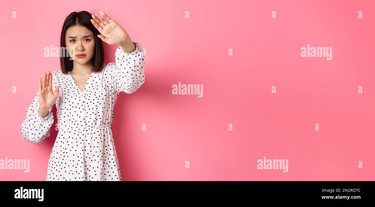 Timid and scared asian woman defending herself, raising arms in ...