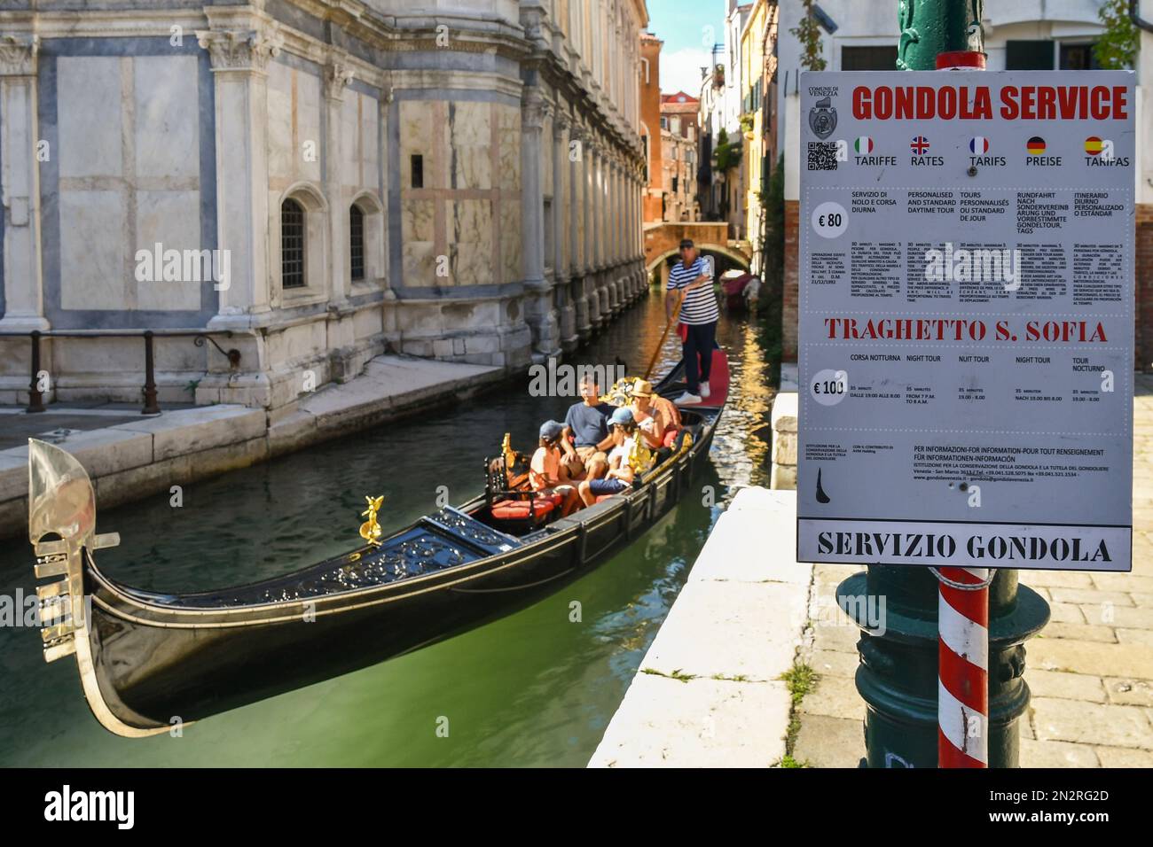 Gondola with tourists on Rio dei Miracoli canal and a sign with the ...