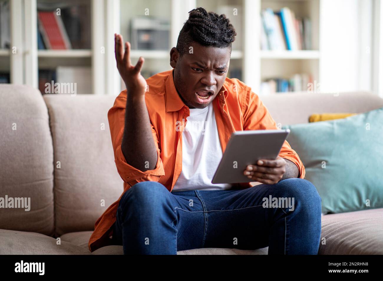 Angry black guy gesturing, receive bad message on pad Stock Photo - Alamy