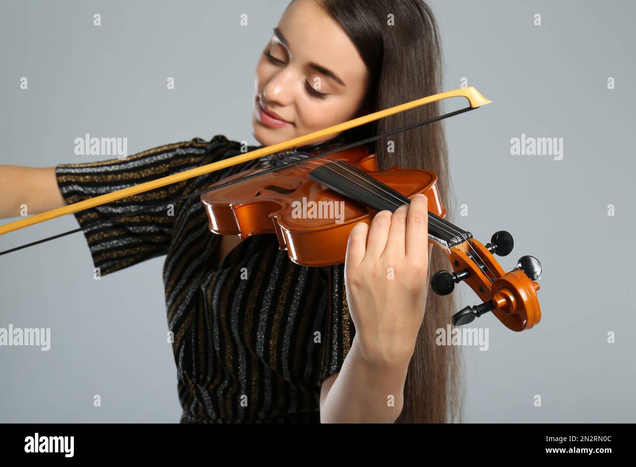 Beautiful woman playing violin on grey background, focus on hand Stock ...