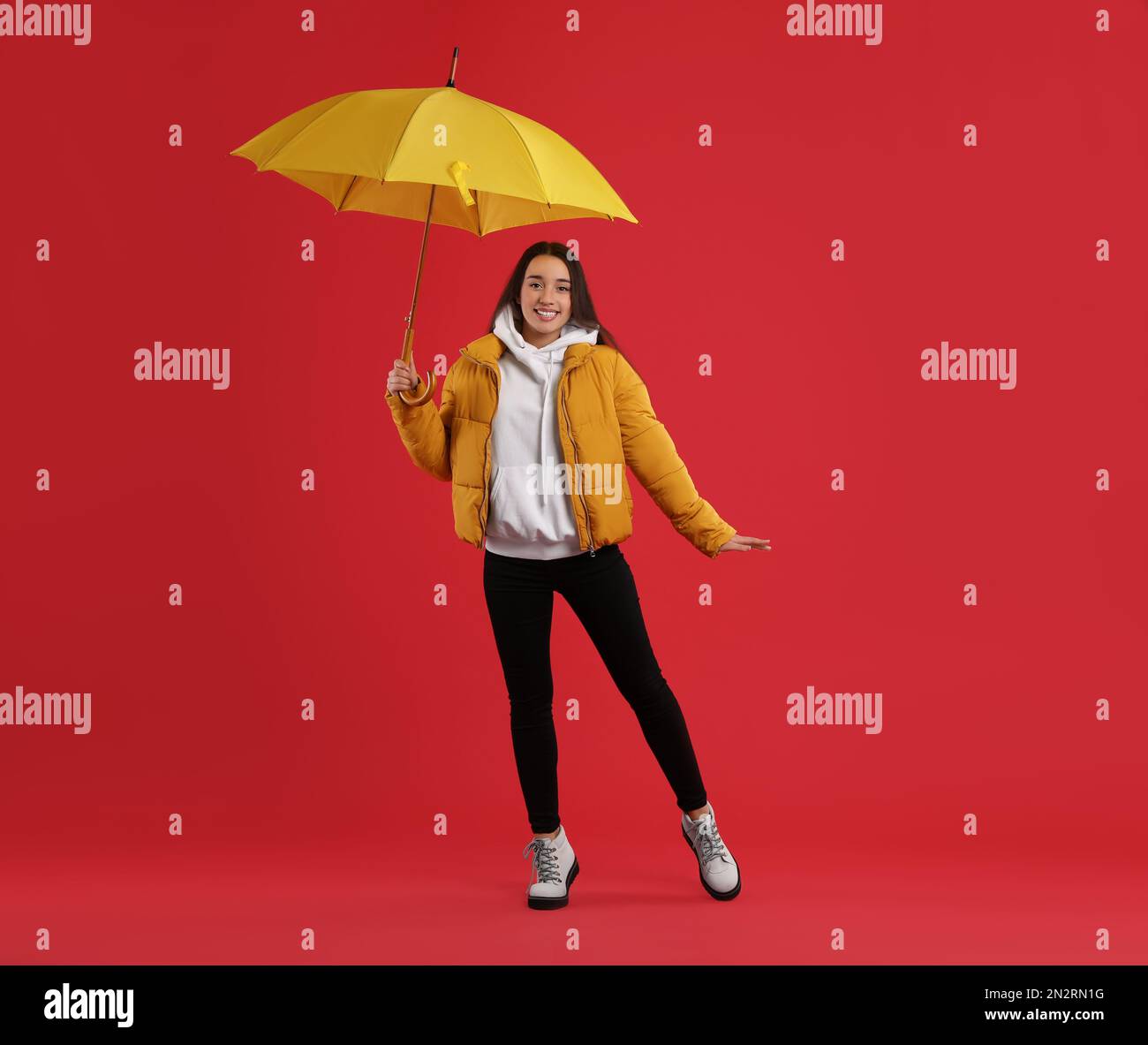 Woman with umbrella caught in gust of wind on red background Stock ...