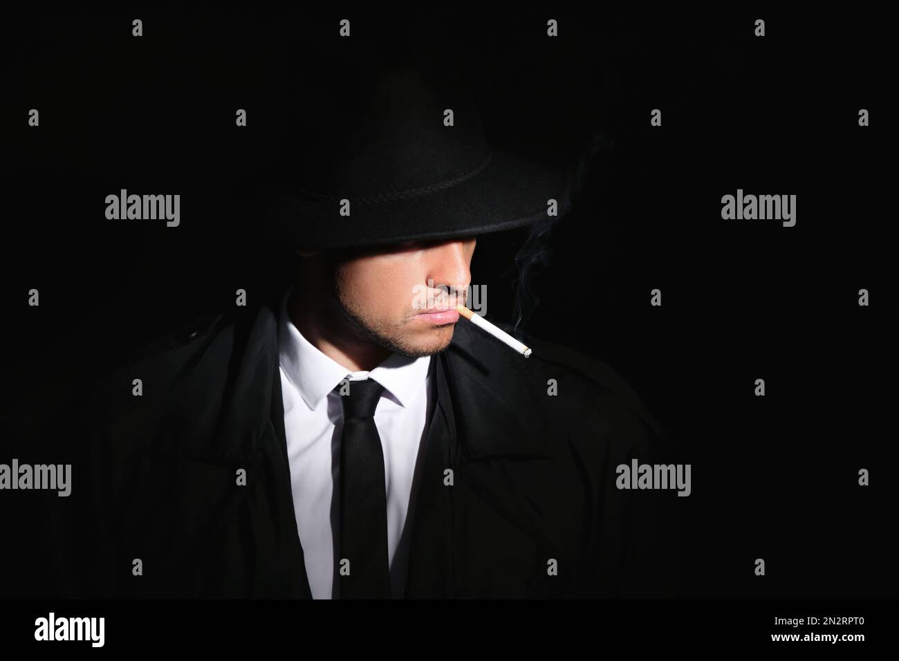 Old fashioned detective smoking cigarette on dark background Stock ...