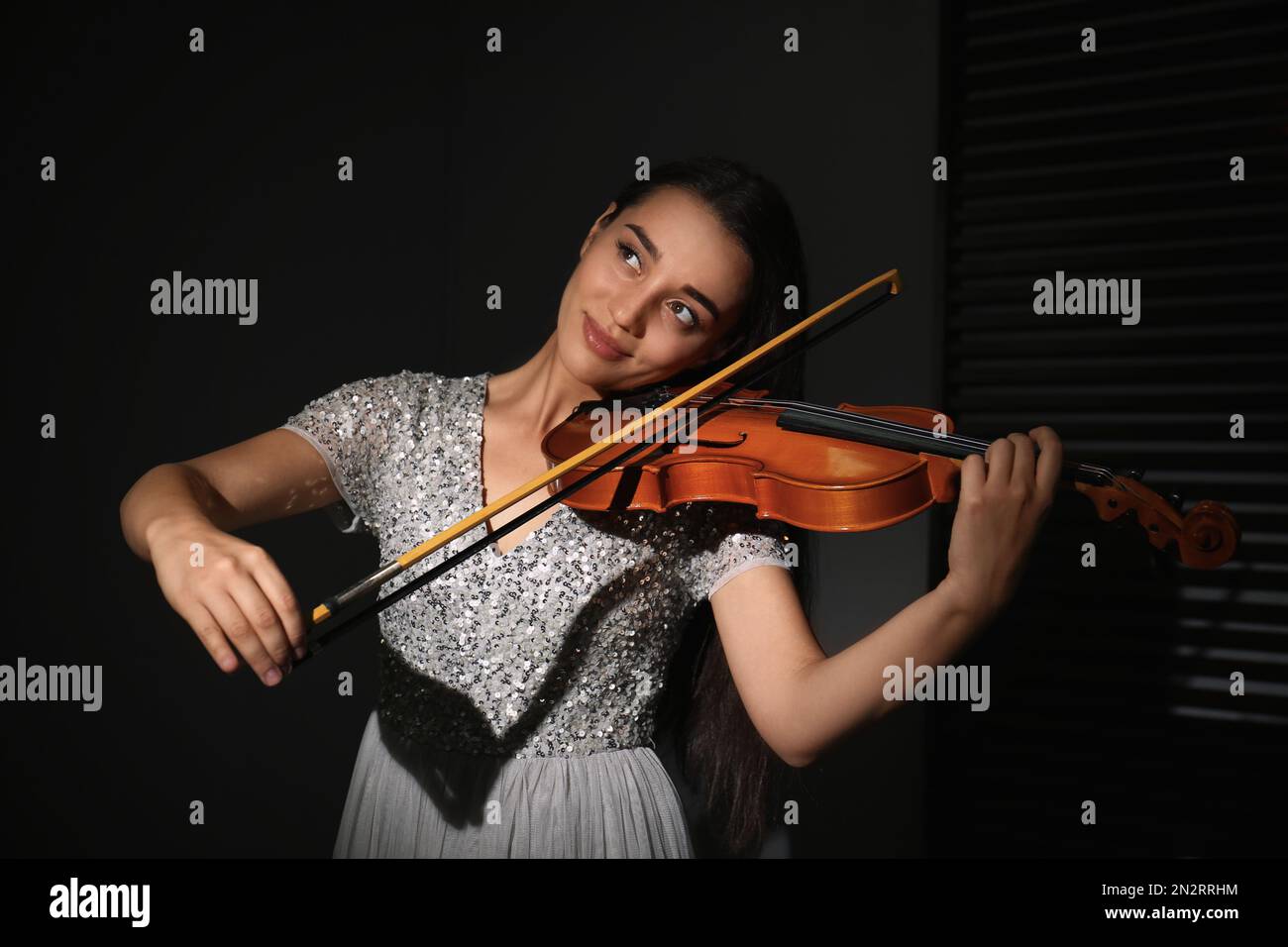 Beautiful young woman playing violin in dark room Stock Photo - Alamy