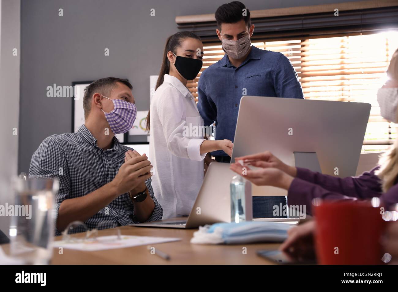 Group of coworkers with protective masks in office. Business meeting ...