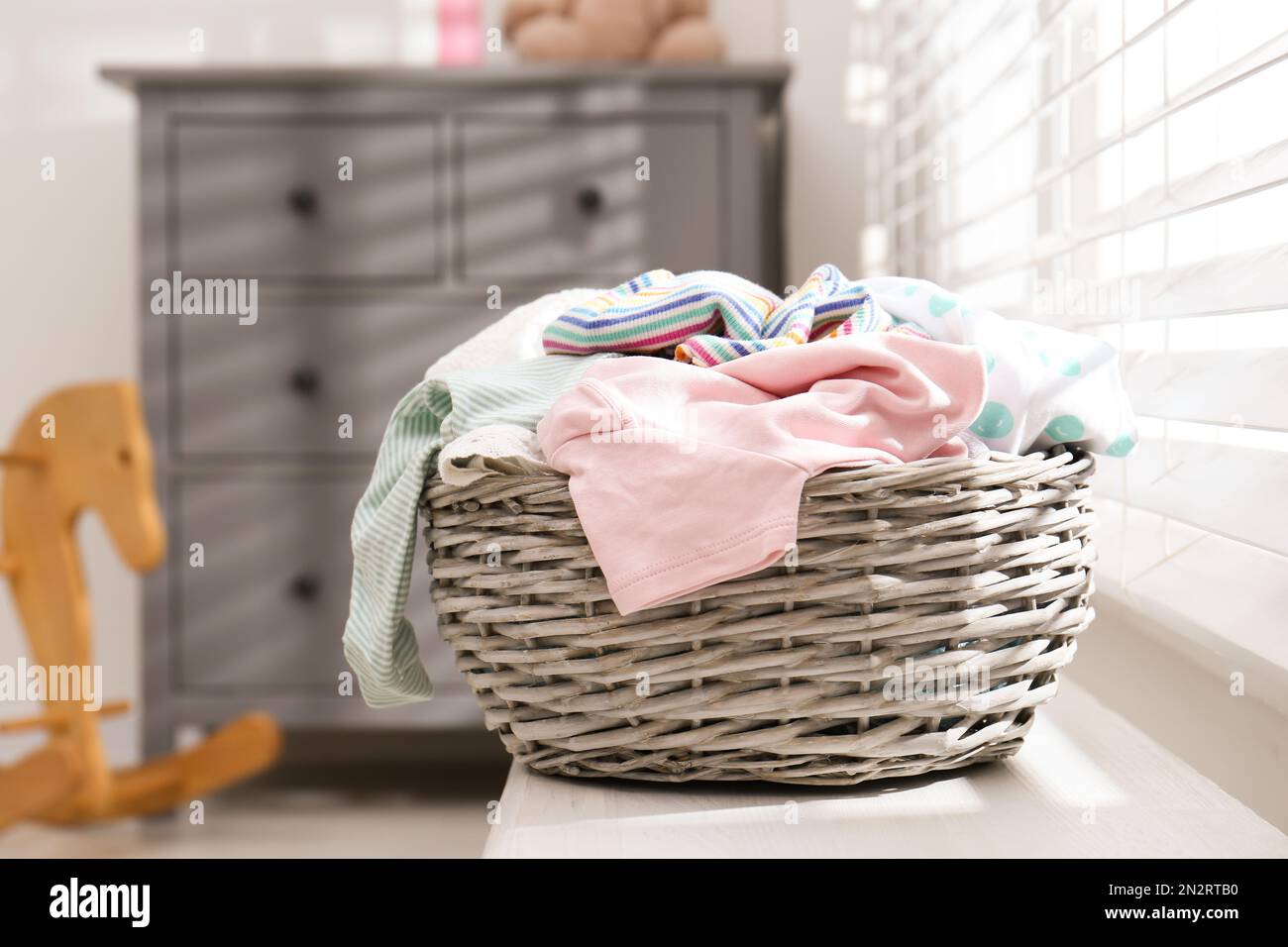 Wicker laundry basket with different clothes on window sill indoors ...
