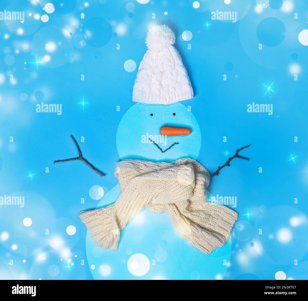 Snowman with hat and scarf on light blue background, flat lay. Bokeh ...