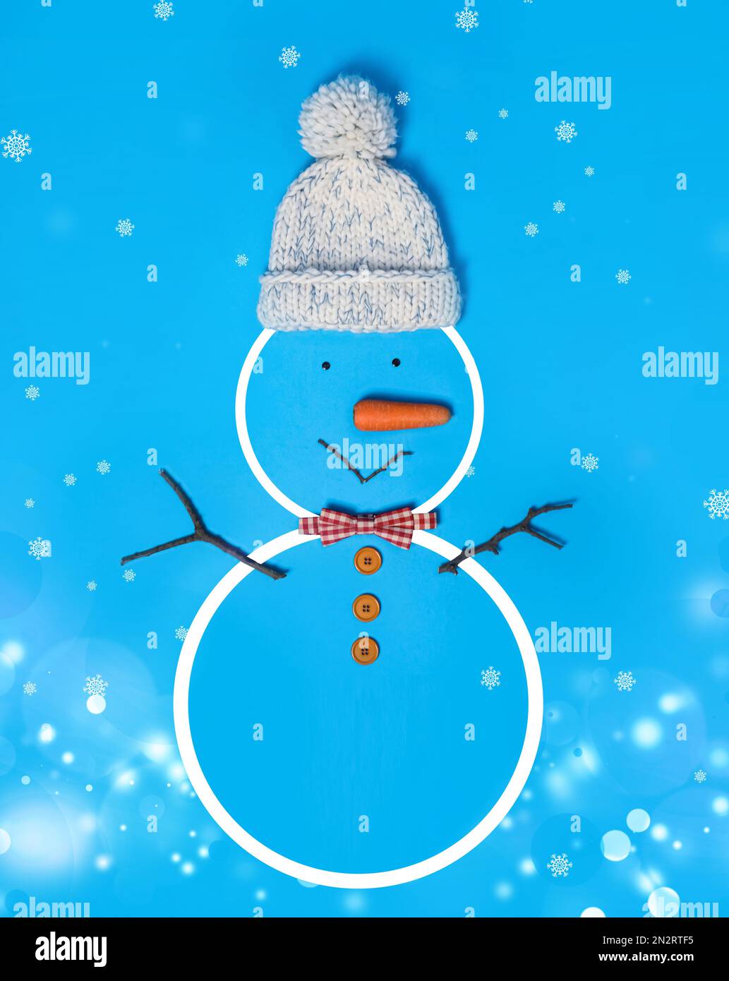 Snowman with hat and bow tie on light blue background, flat lay. Bokeh ...