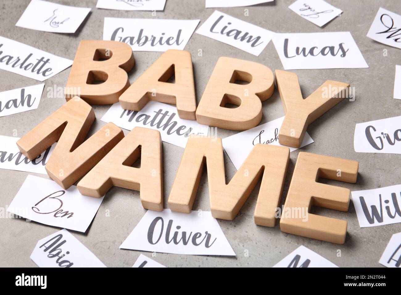 Paper sheets with different baby names, and wooden letters on grey ...