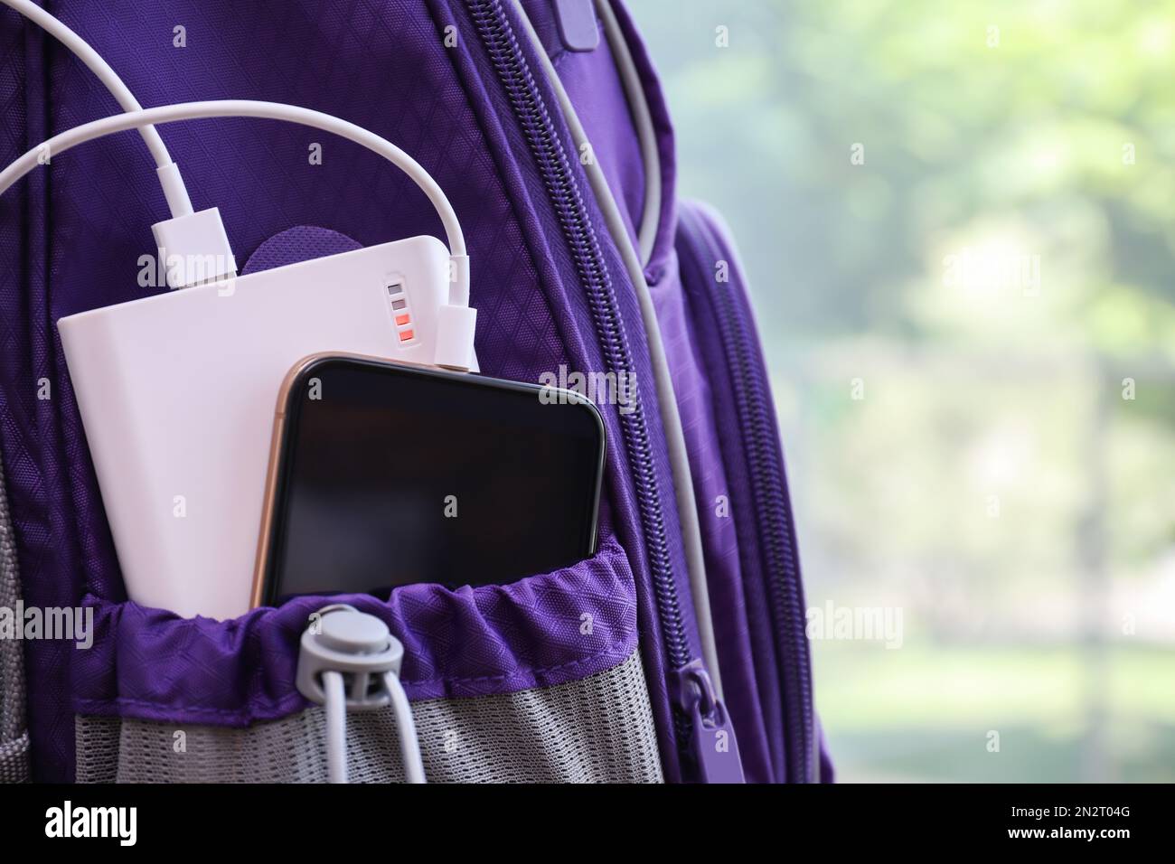 Charging mobile phone with power bank in purple backpack, closeup Stock ...