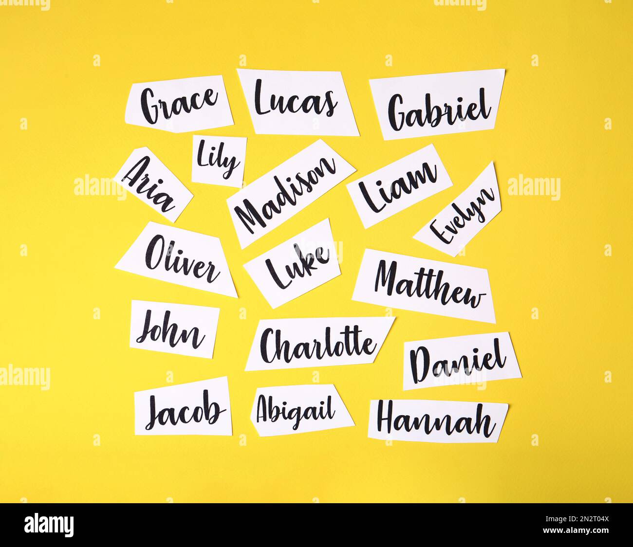 Paper sheets with written different baby names on yellow background ...