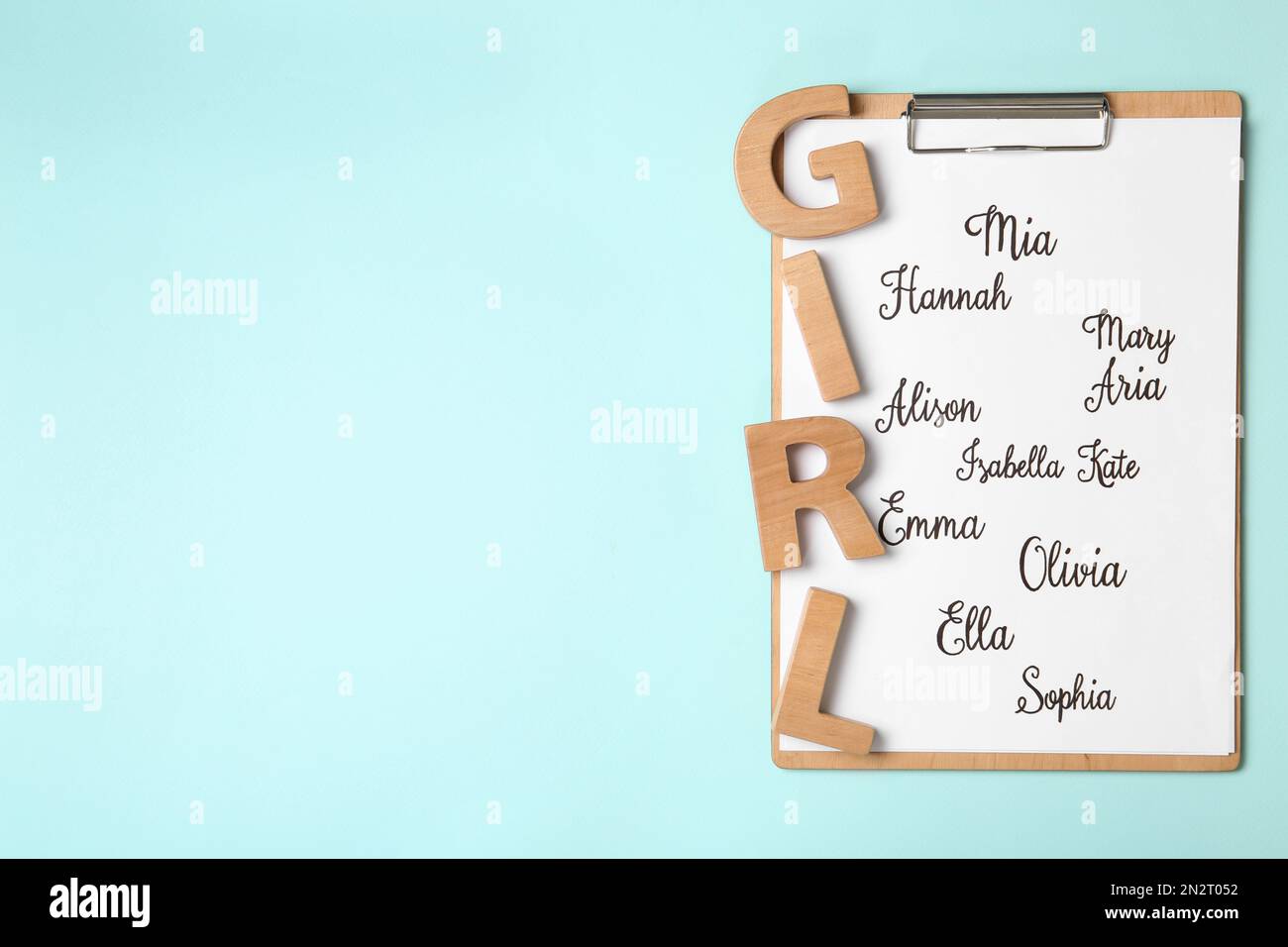 Clipboard with list of baby names and wooden letters on light blue ...