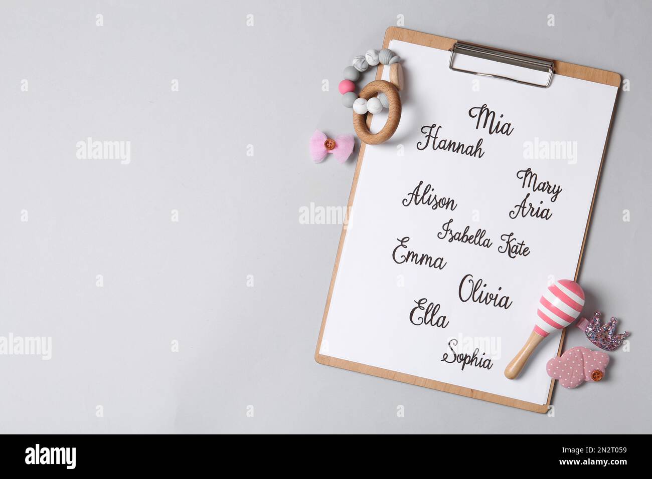 Clipboard with different baby names and toys on grey background, top ...