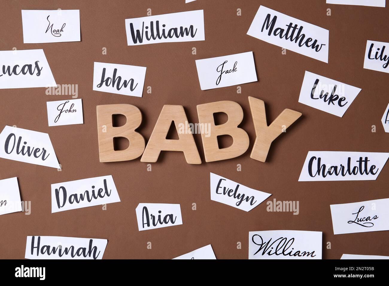 Paper sheets with written different baby names and wooden letters on ...