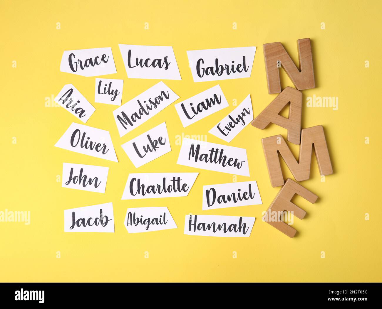 Paper sheets with written different baby names and wooden letters on ...