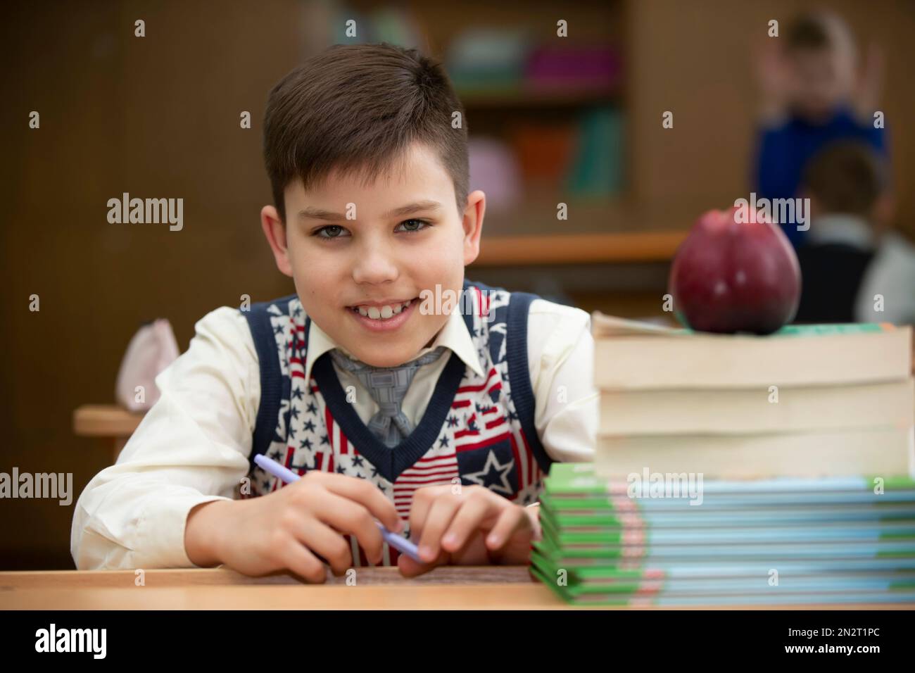 Schoolboy at the desk. Boy in the classroom with books and an apple ...