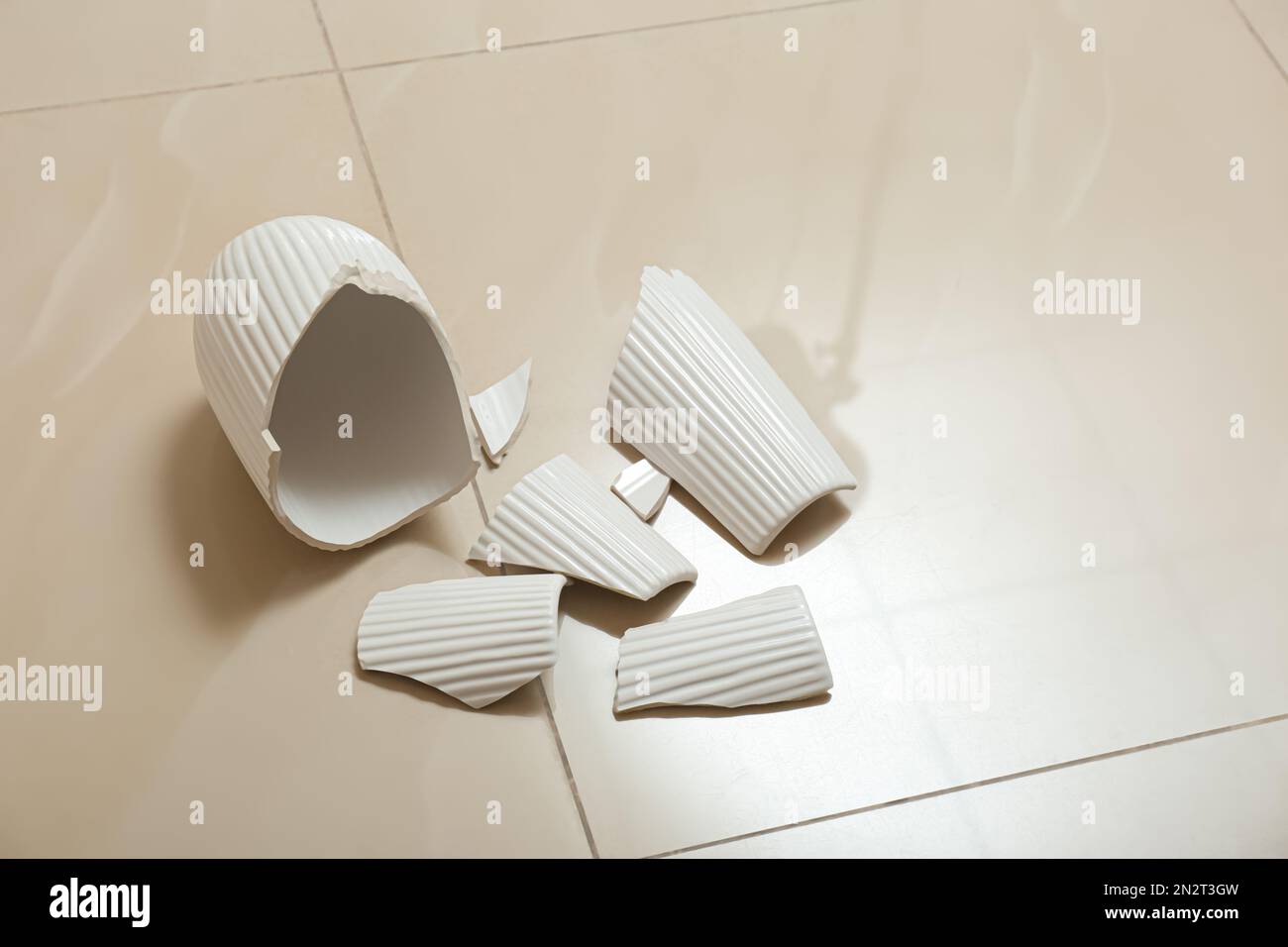 Broken white ceramic vase on floor indoors Stock Photo - Alamy