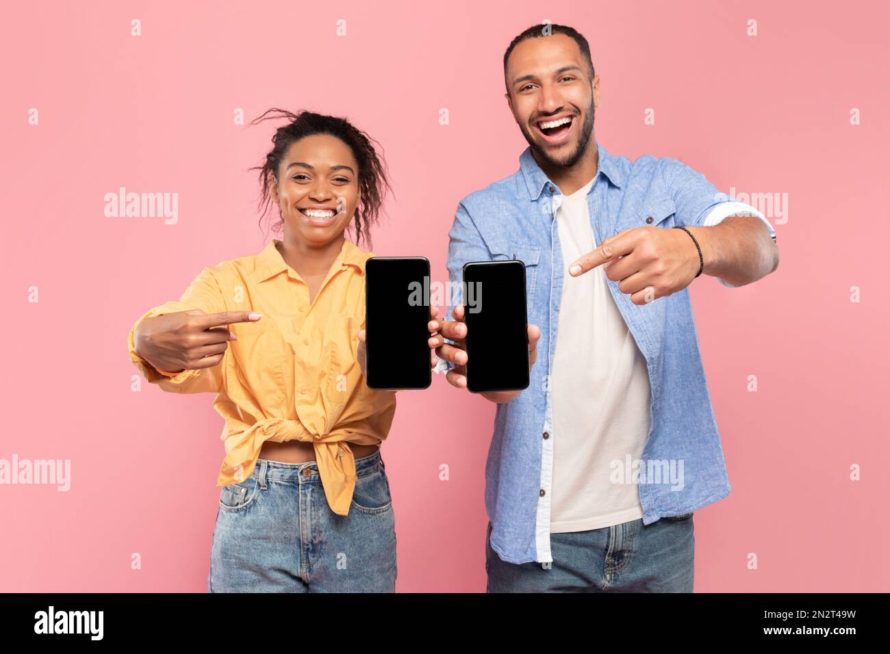 We like this app. Happy couple showing two smartphones with black ...